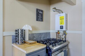 Uma cozinha com fogão a gás, aquecedor de água e um armário de temperos.