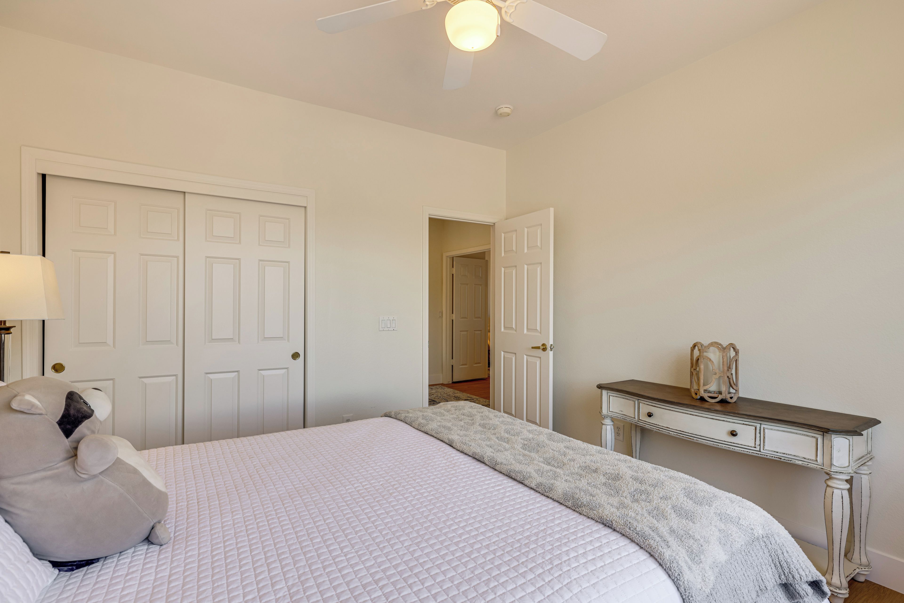 Quarto com cama, mesa de cabeceira, abajur e cômoda.