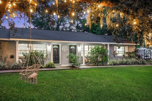 Uma casa com varanda, cadeira de balanço e gramado bem cuidado.