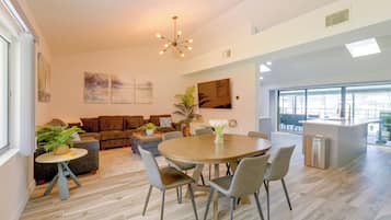 Uma sala de estar moderna com área de jantar, um conjunto de sofás, uma mesa de centro e uma mesa de jantar com cadeiras.