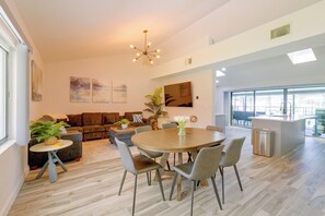 Uma sala de estar moderna com área de jantar, um conjunto de sofás, uma mesa de centro e uma mesa de jantar com cadeiras.
