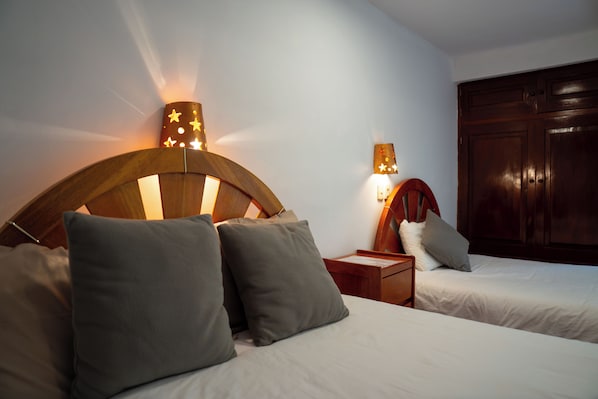 Quarto de hotel com duas camas, cabeceiras de madeira e abajures laterais.