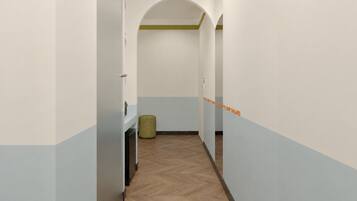 Um corredor com piso em padrão herringbone, paredes brancas com uma faixa azul clara e uma parede de destaque verde.