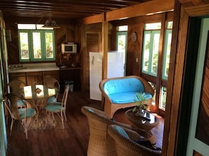 Um interior de madeira com uma mesa de jantar, cadeiras, um frigorífico e uma televisão.