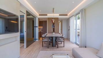Um interior moderno com área de refeições, um sofá e vista para o exterior.