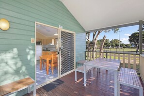 Quarto com mesa e cadeiras de jantar, cozinha e vista para o exterior.