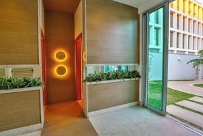 Um interior moderno com parede de madeira, luminárias circulares e porta de vidro que dá para o exterior.