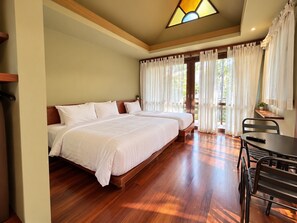 Quarto de hotel com duas camas, uma mesa de jantar e vista para o exterior.