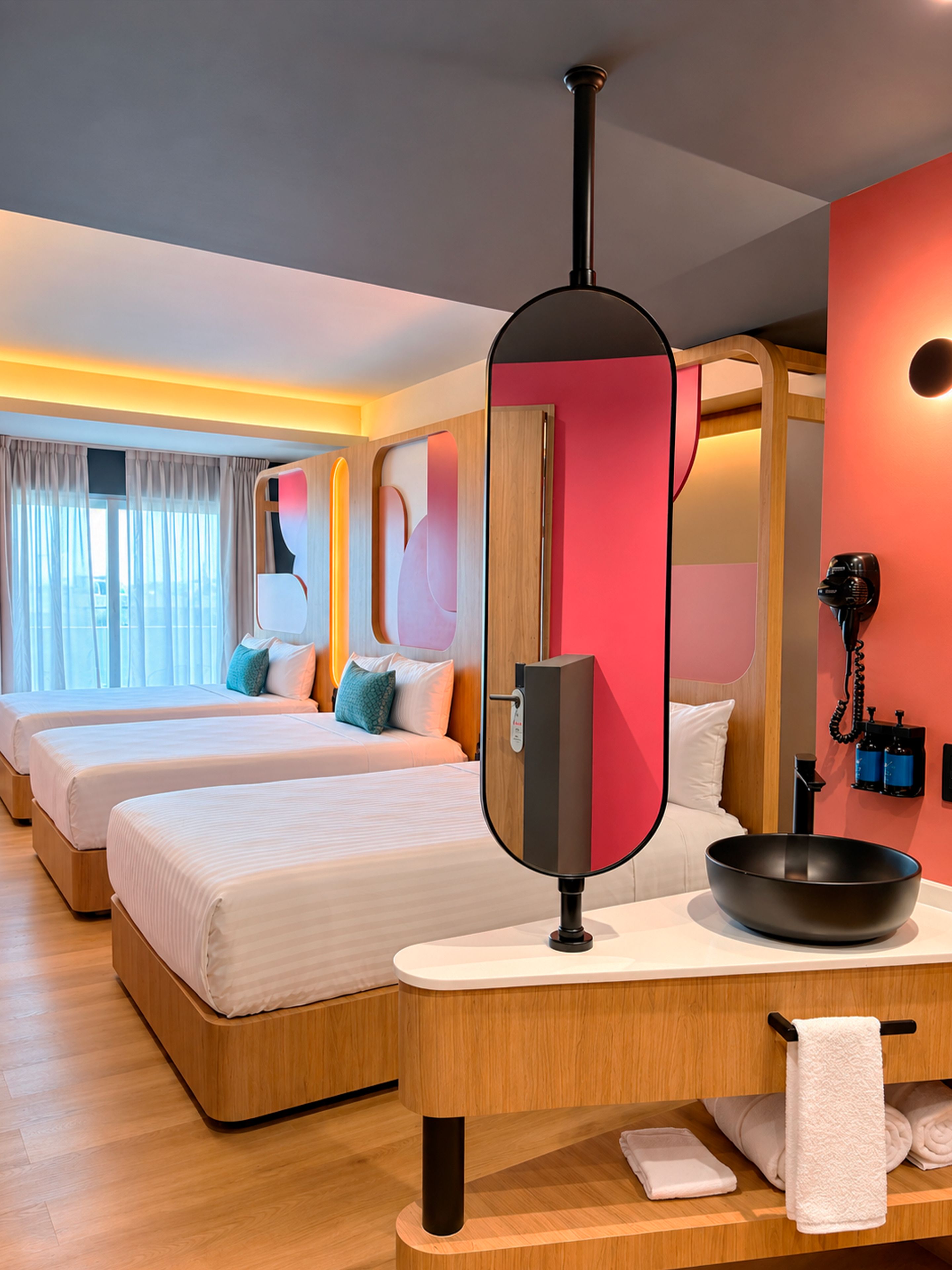 Quarto de hotel com duas camas, um espelho, uma tigela preta, um secador de cabelo e um porta-toalhas.