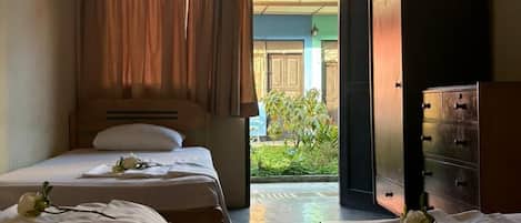 Quarto de hotel com duas camas, cabeceira de madeira, guarda-roupa e vista para o exterior.