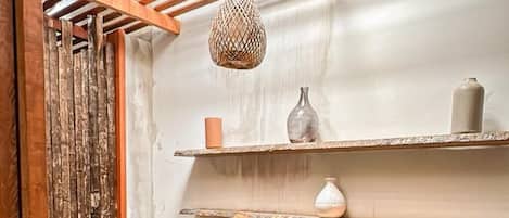 Um quarto com teto de madeira, uma mesa redonda com cadeiras e estantes com objetos decorativos.