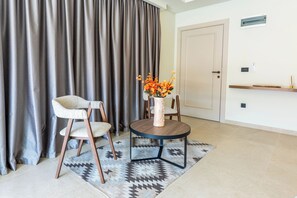 Um quarto com uma mesa redonda, duas cadeiras, um vaso com flores e uma porta.