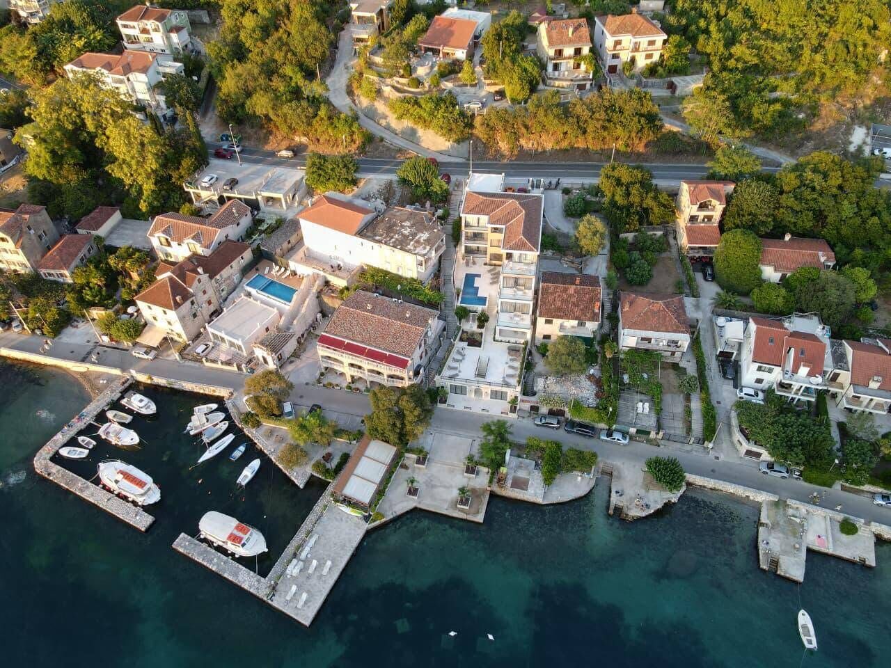 Vista aérea de uma área residencial costeira com casas, um porto de iates e um cais.