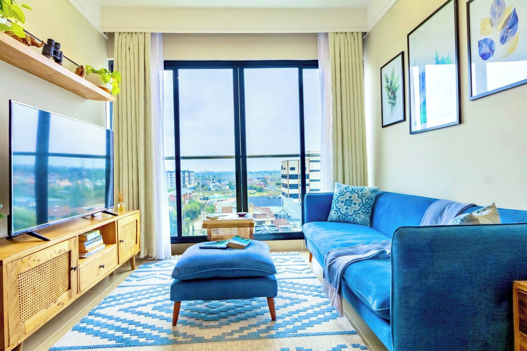Uma sala de estar moderna com uma janela grande, um sofá, uma TV e um armário de madeira.