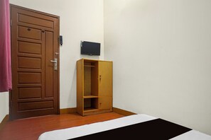 Quarto com porta de madeira, um pequeno armário e uma cama com colcha preta e branca.