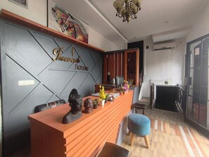Uma receção com design moderno, um candelabro e um letreiro afixado na parede com o nome 'Tanwah House'.