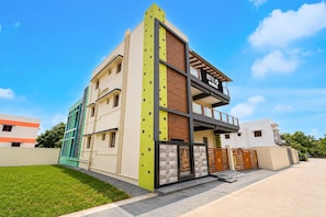 Um hotel moderno com estrutura em vários andares, varanda no andar superior e entrada com portão.