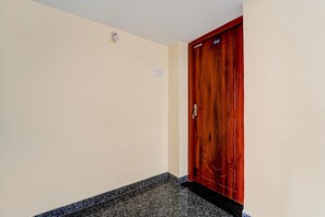 Corredor com uma porta de madeira com a placa '202' e um interruptor de luz na parede.