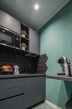 Uma cozinha moderna com micro-ondas Bosch, chaleira e máquina de café no balcão.