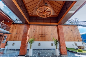 Varanda de madeira com uma placa indicando 'Balcony House' e uma roda de madeira decorativa.