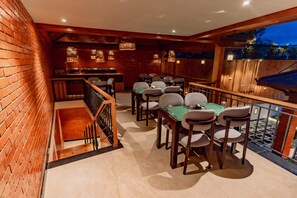 Restaurante com parede de tijolos, teto de madeira e uma varanda com vista para o céu azul.