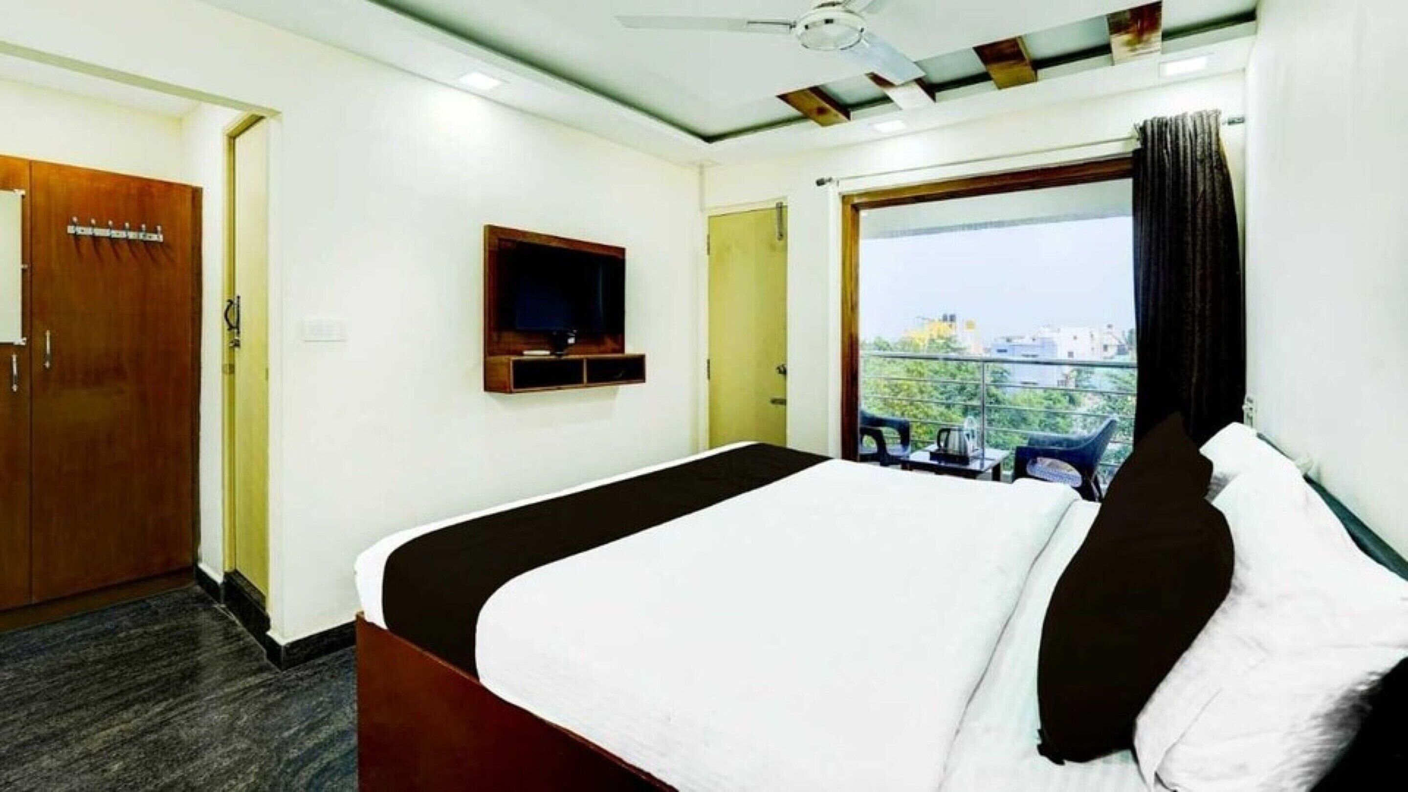 Quarto de hotel com cama, televisão, janela com vista e porta.