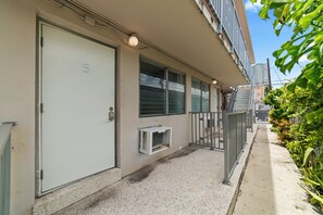 Um edifício com porta fechada, aparelhos de ar condicionado e portão.