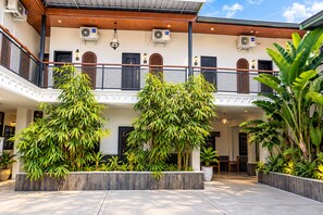 Um edifício com um pátio coberto, vários andares e áreas de estar ao ar livre.