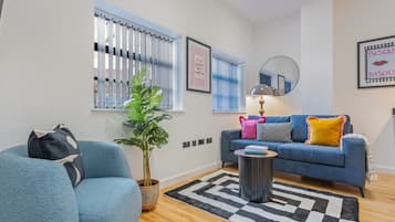 Uma sala de estar moderna com um sofá azul, uma mesa de centro redonda e um vaso com planta.