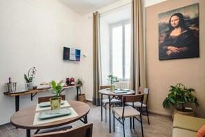 Uma área de refeições com uma mesa redonda, cadeiras e plantas em vasos.
