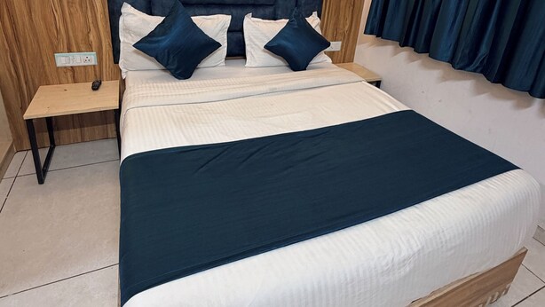 A bed with a wooden headboard, a bedside table, and a power outlet.