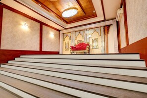 Uma escadaria imponente leva a um quarto com sofá vermelho e decoração requintada.