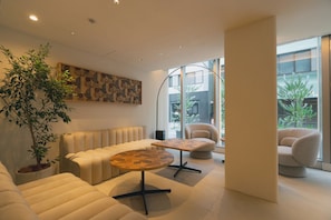 Uma sala de estar moderna com sofá, mesa de centro e uma poltrona. Há uma janela grande que oferece vista para o exterior.