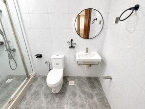 Casa de banho com sanita, lavatório e chuveiro.