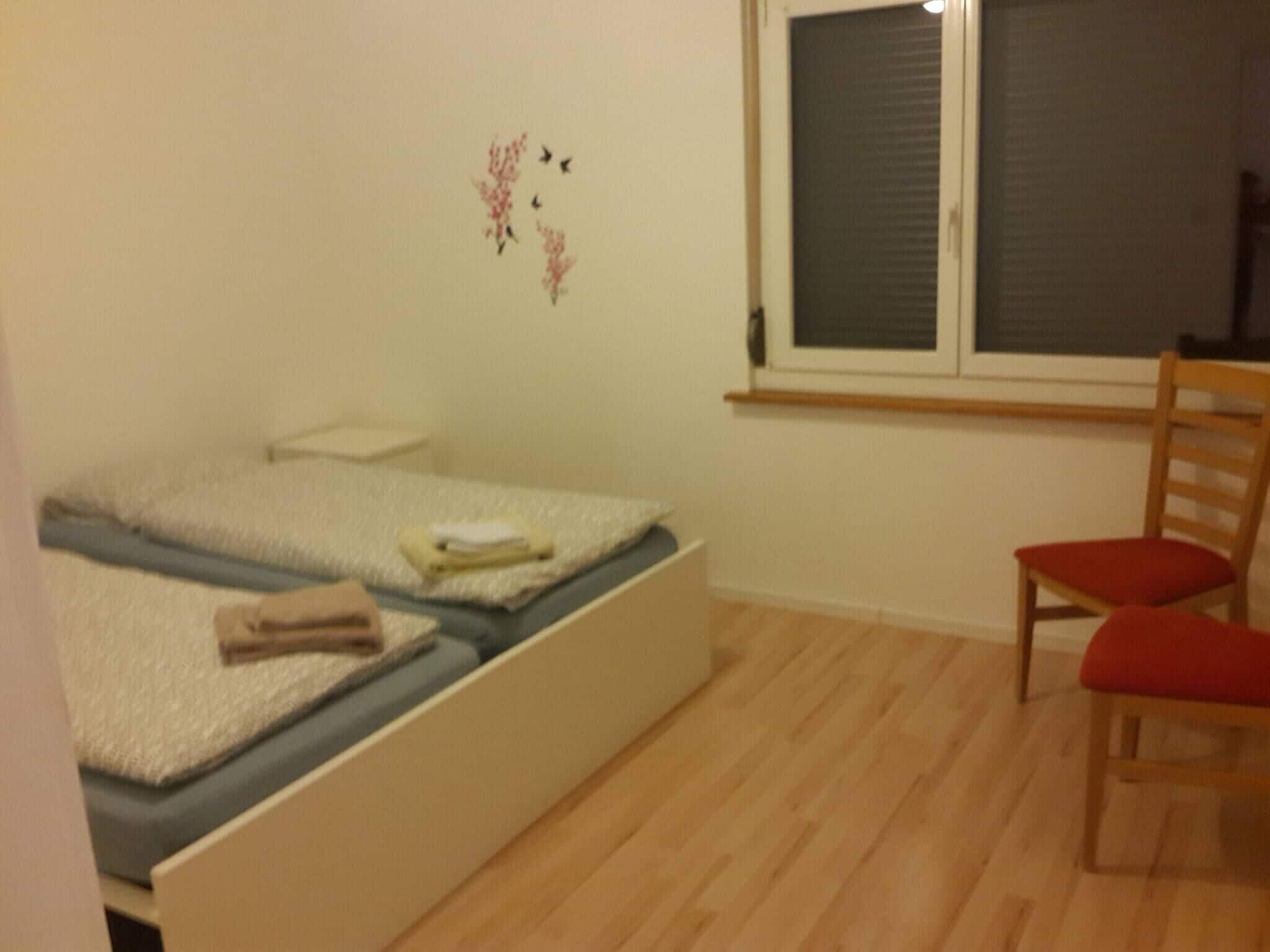 Quarto com cama, cadeira, janela e decoração na parede.