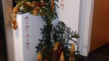 Uma árvore de Natal com enfeites e luzes, posicionada em frente a uma parede com decoração em letras decorativas.