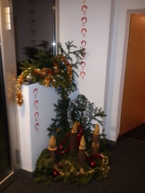 Uma árvore de Natal com enfeites e luzes, posicionada em frente a uma parede com decoração em letras decorativas.