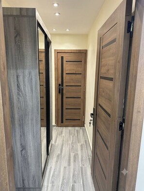 Um corredor com portas de madeira e chão de azulejos.