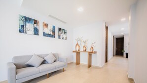 Um interior moderno com sofá cinzento, mesinhas de cabeceira em madeira e arte abstrata na parede.