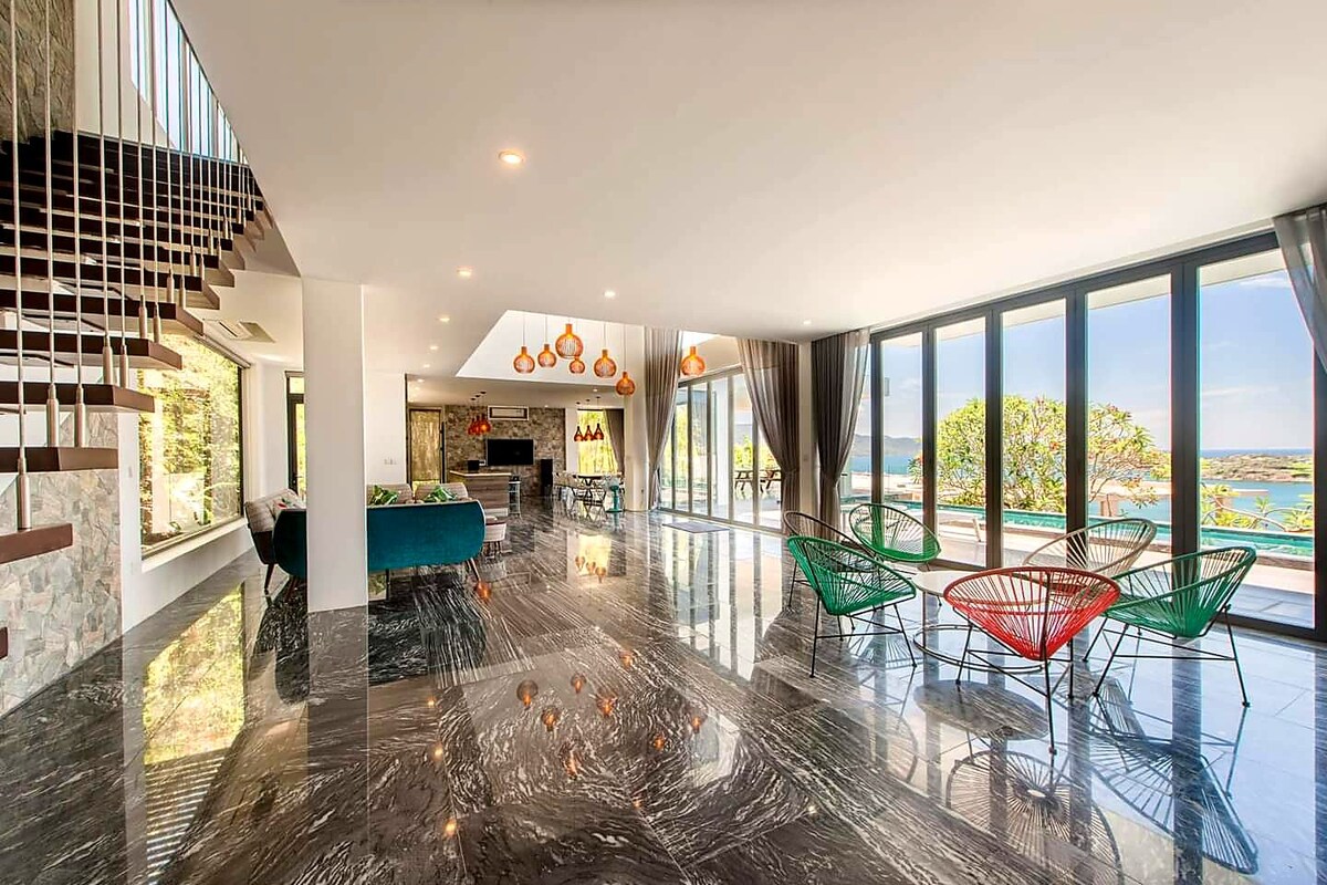 Uma sala de estar ampla com teto alto, escada e vista para o exterior.