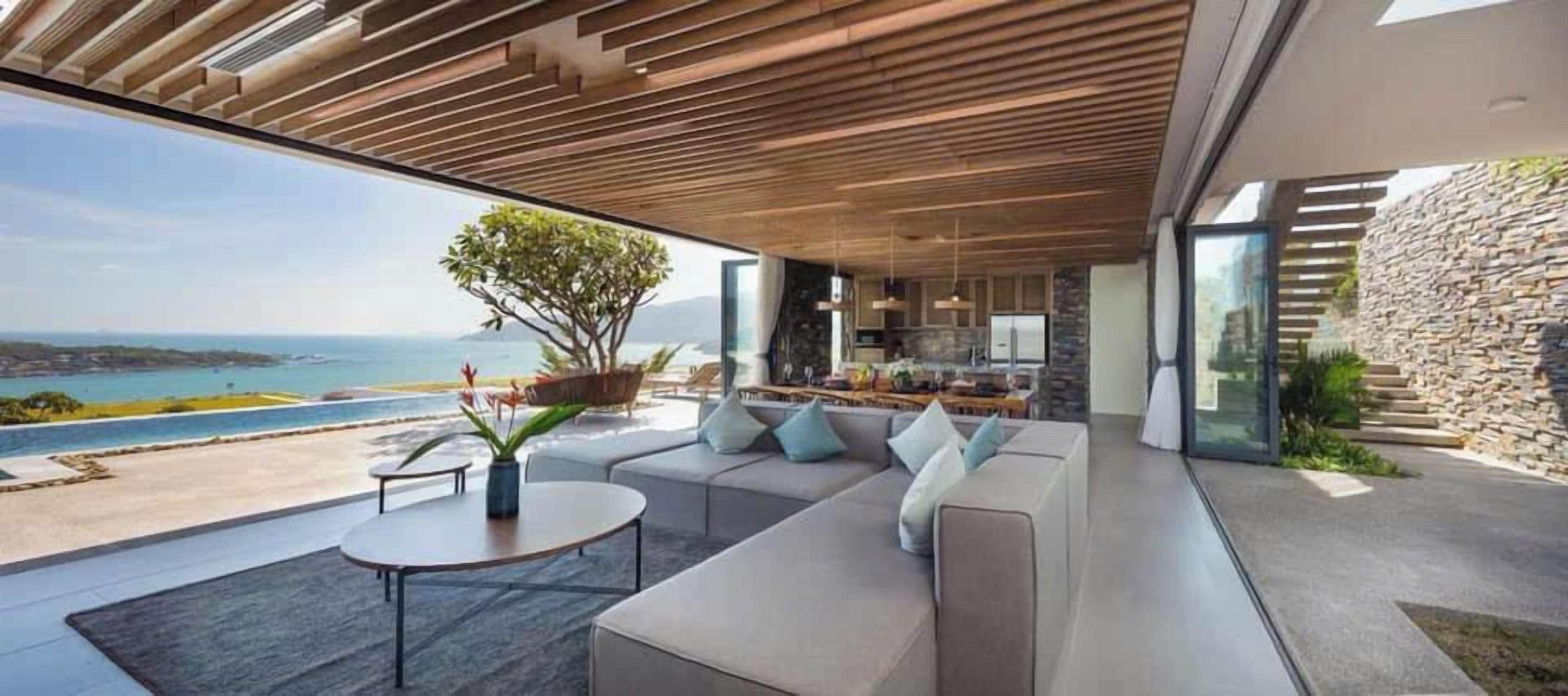 Um interior moderno com área de estar, espaço para refeições e vista para o mar.