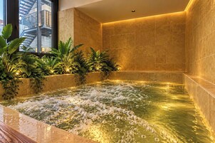 Uma área de spa com hidromassagem, paredes revestidas de azulejos e plantas.
