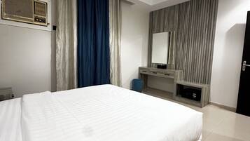 Quarto de hotel com uma cama grande, uma escrivaninha com cadeira, um espelho e um radiador.