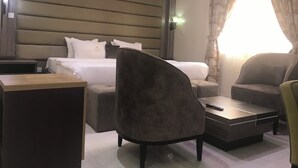 Quarto de hotel com cama, sofá, mesa de centro e escrivaninha.