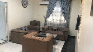 Uma sala de estar com um sofá modular, uma mesa de centro e uma televisão.