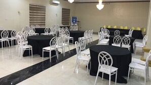 Uma sala de conferência com várias mesas e cadeiras, aparelhos de ar condicionado e lustres.