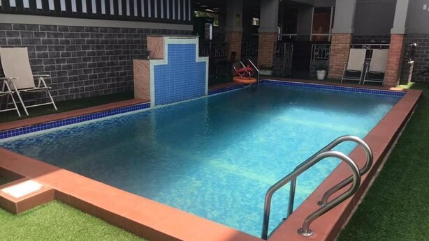 Uma piscina interna com borda azulejada, corrimão de metal e um pequeno degrau para entrar na piscina.