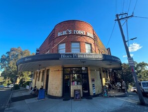 Edifício de tijolos com fachada curva e placa que diz 'Blues Point Hotel'.