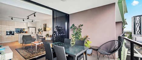 Um apartamento moderno com área de jantar, cozinha e varanda com vista para a cidade.