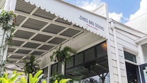 Um edifício com uma placa exibindo 'SIXES AND SEVEN VINS' e uma área de entrada coberta com plantas.